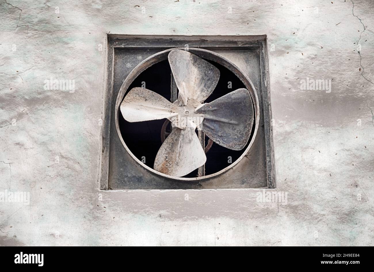 A wall fan on a non-descript building provides ventilation in the humid ...