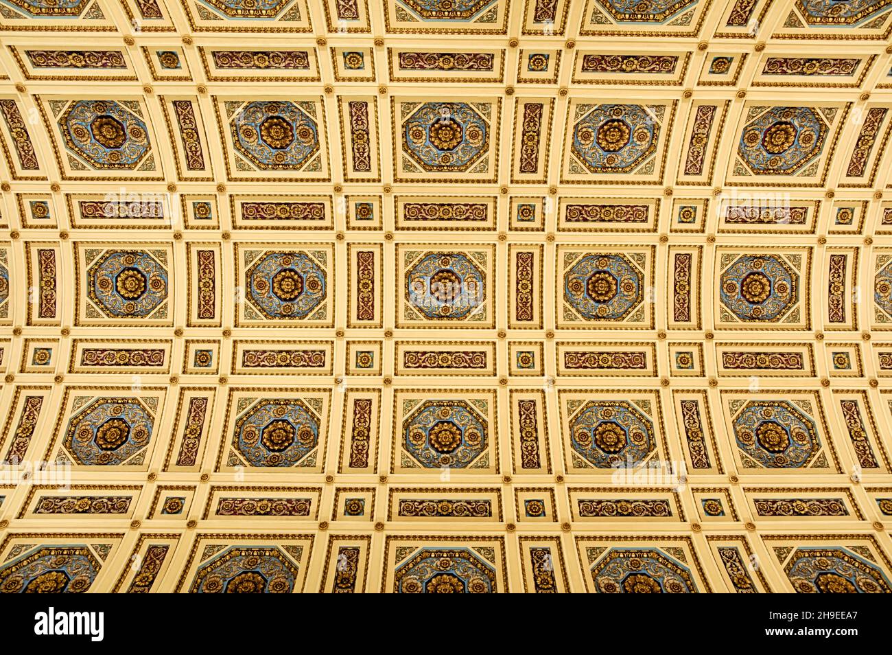 Ornate details of a ceiling painted with gold and other patterns is a ...