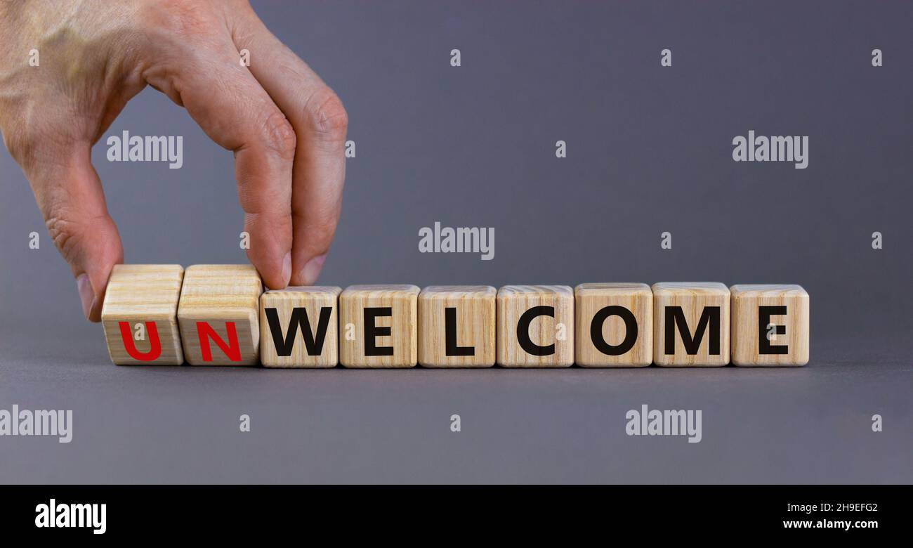 Welcome or unwelcome symbol. Businessman turns wooden cubes and changes ...
