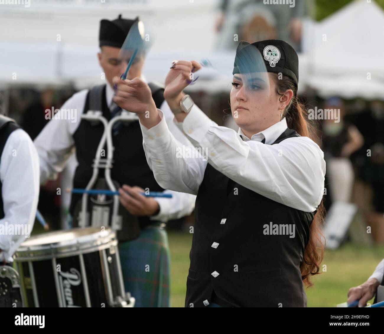 A drummer in a Highland Scottish pipe band flourishes or twirls her ...