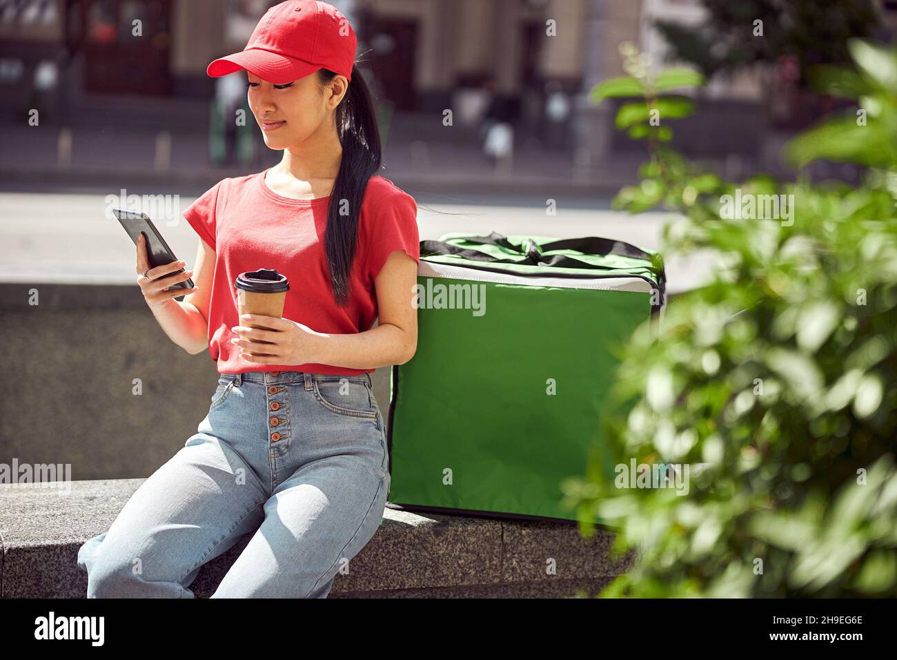 Female delivery worker resting with mobile outdoors Stock Photo - Alamy
