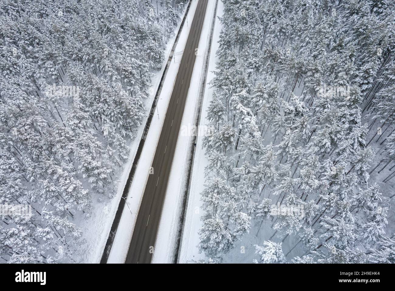 Aerial view of asphalt highway leading through frosty winter forests ...