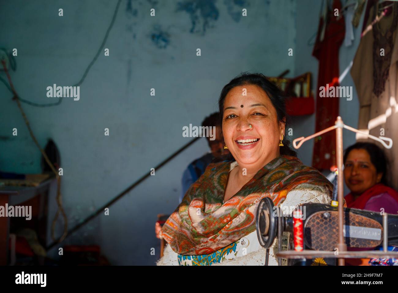 Friendly local Indian tailor working at a traditional sewing machine ...