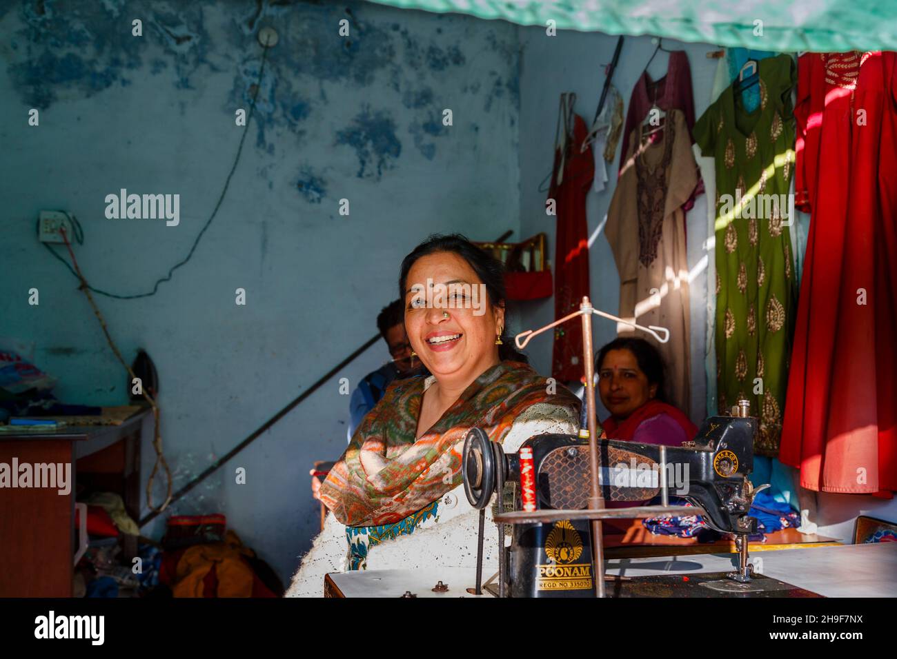Friendly local Indian tailor working at a traditional sewing machine ...
