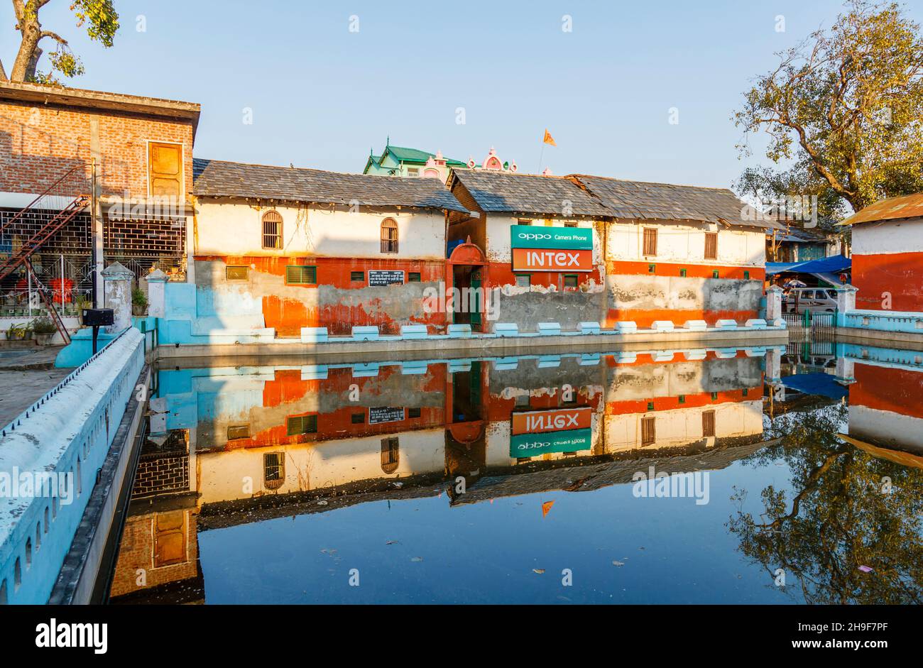 Old buildings reflected in the village tank (pond) in Pragpur, a ...
