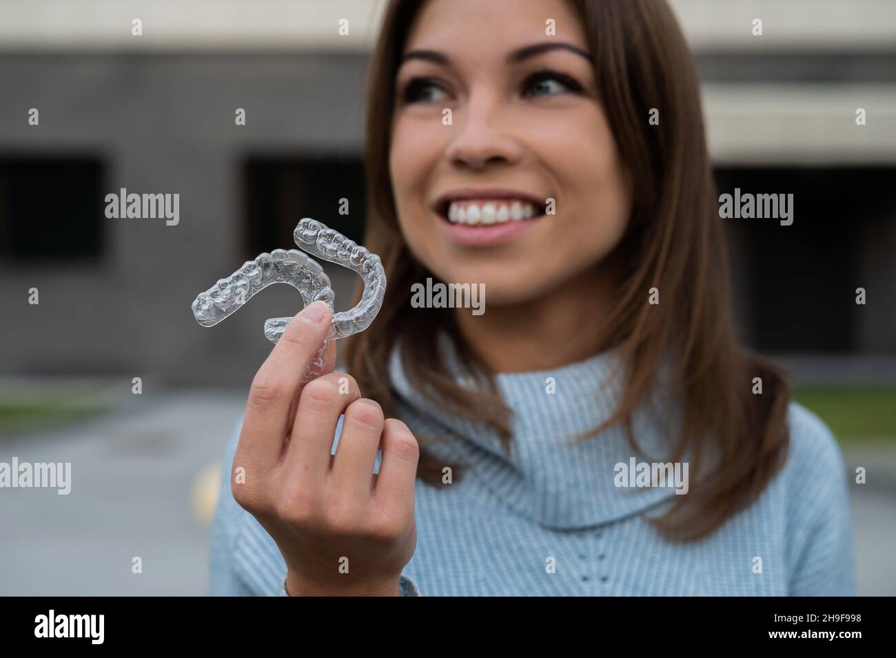 Caucasian woman with white smile holding transparent removable retainer ...