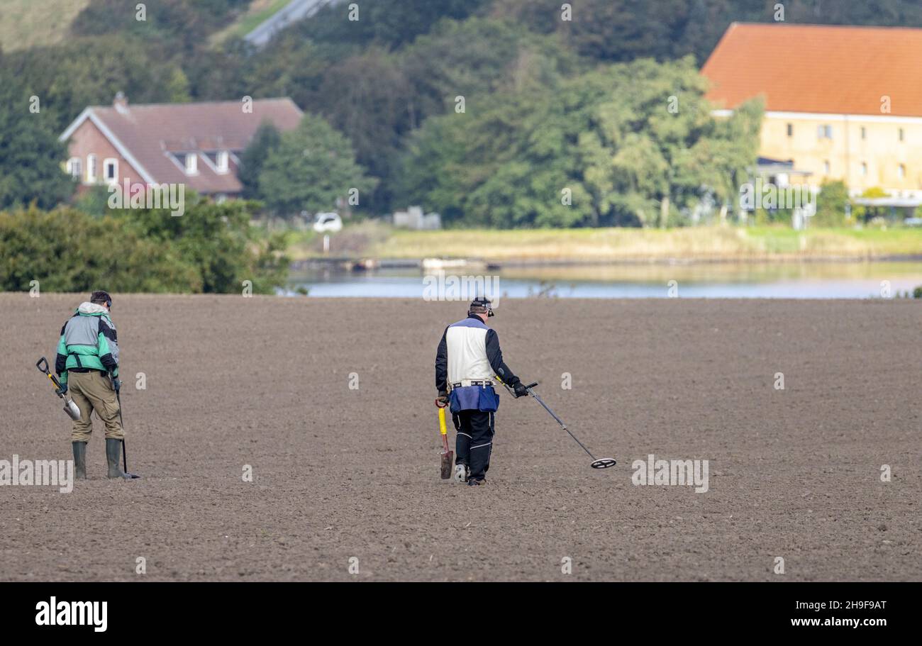Metal detecting on a field near the water Stock Photo - Alamy