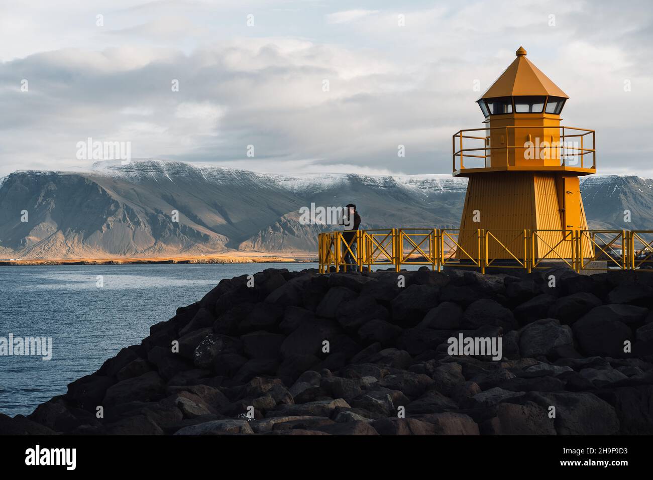 Hofdi Lighthouse surrounded by the sea under a cloudy sky in Iceland ...