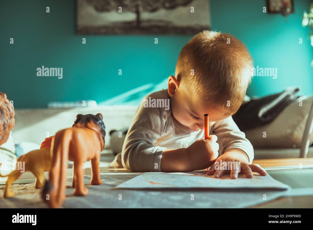 Shallow focus of an adorable toddler drawing with colorful pencils and ...