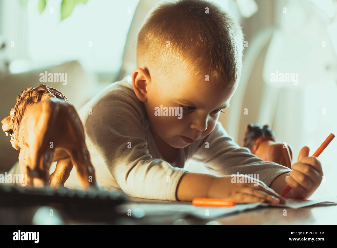 Shallow focus of an adorable toddler drawing with colorful pencils and ...