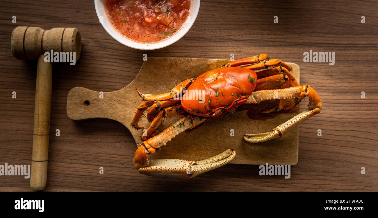 Overhead view of a cooked crab on a kitchen board next to a wooden ...
