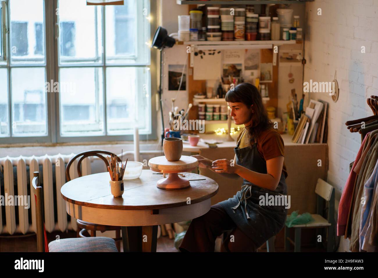 Ceramist in apron molding vase at master class in studio. Young woman ...