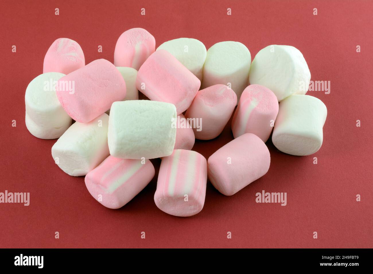 Jumbo marshmallows and jumbo strawberry marshmallows on red background ...