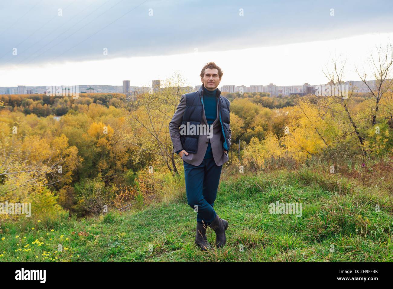 Tall handsome man walking outdoor in yellow autumn forest on the hill ...