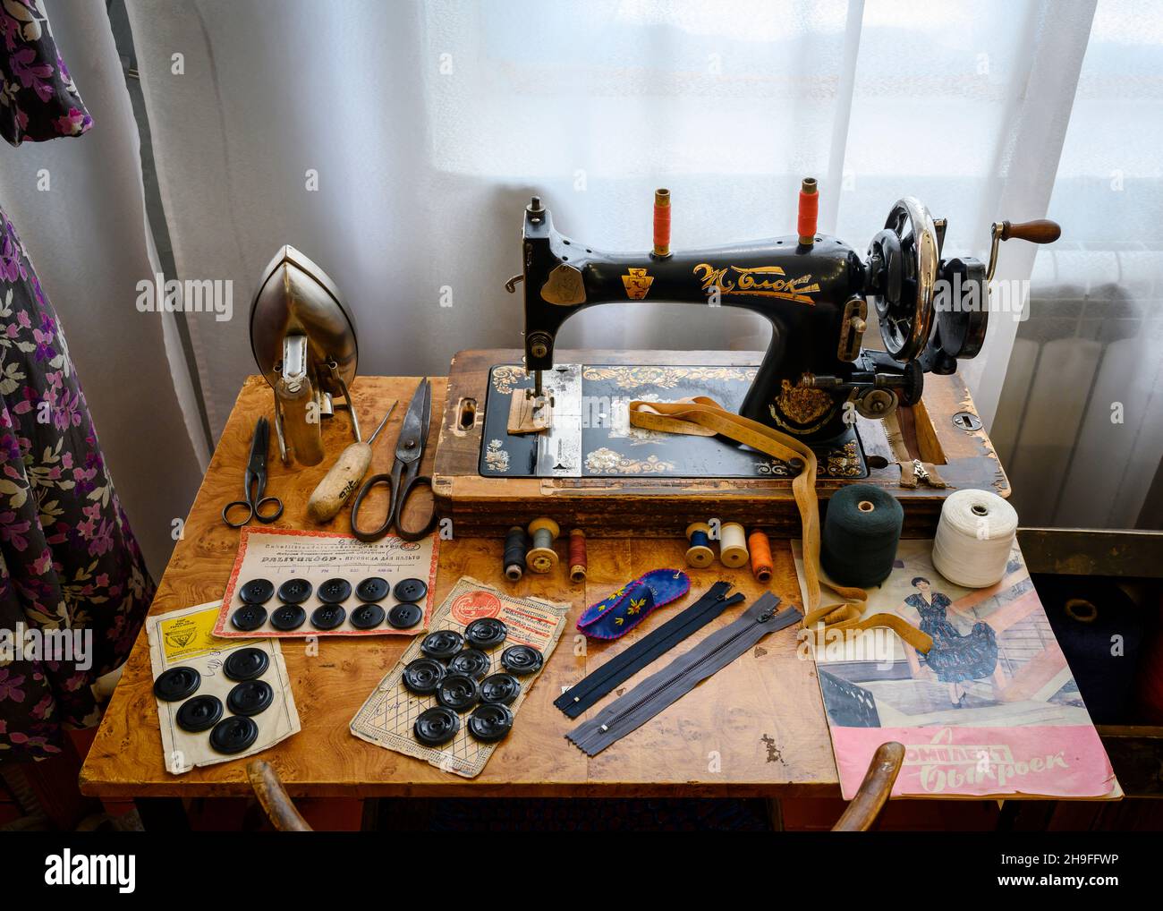 Table with vintage sewing tools: hand sewing machine, iron, scissors ...