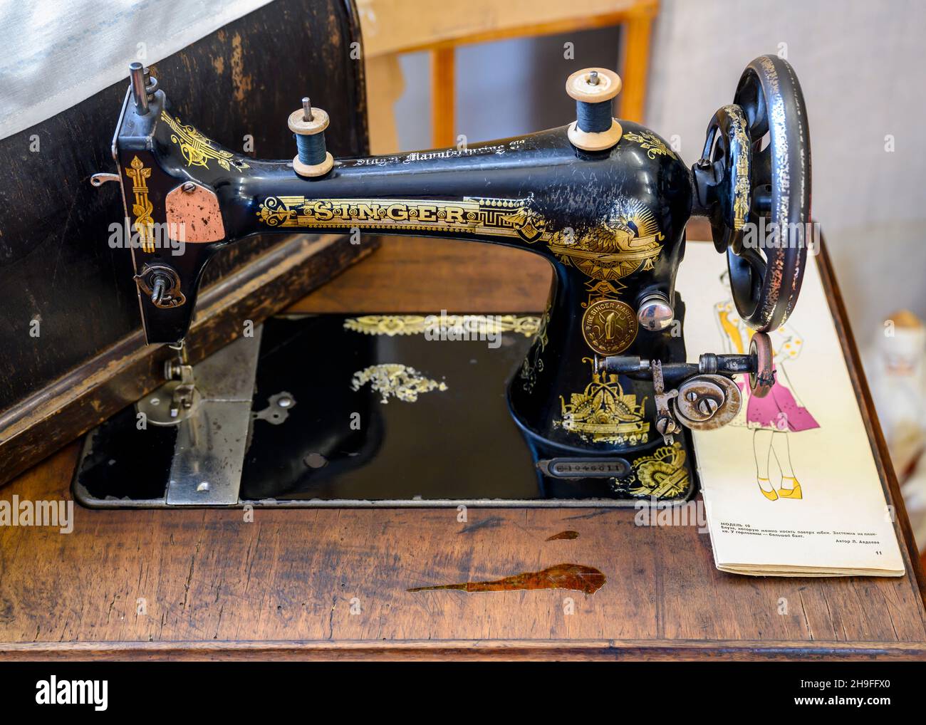 A table with a vintage German hand sewing machine and a sewing magazine ...