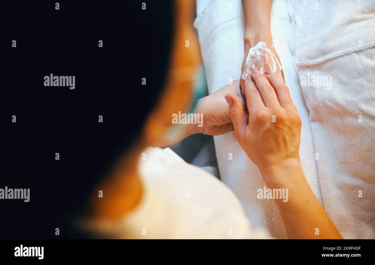Masseuse's hands applying cream to the client's hands. Cosmetology ...