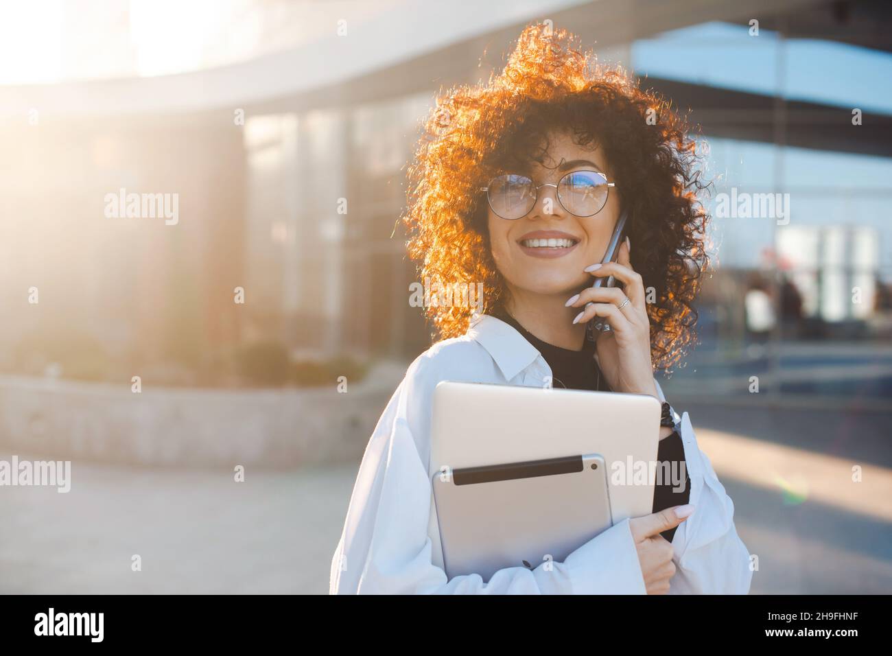 Close up portrait of a curly-haired businesswoman walking outdoor ...