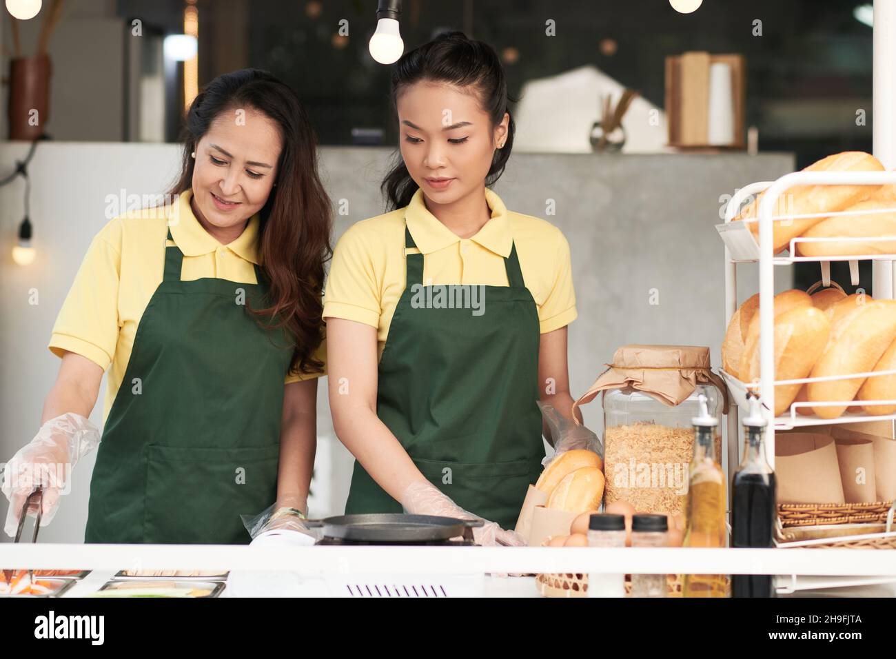 Mobile kitchen owner explaining new worker how to cook street food ...