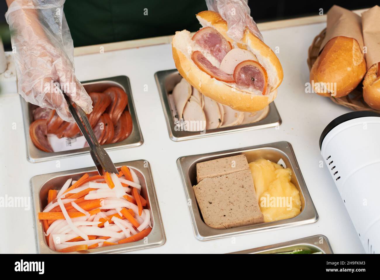 Closeup image of cook adding onion and carrot in sandwich for customer ...