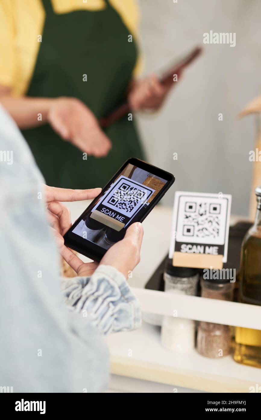 Hands of female customer scanning QR code a street food cart to upload ...