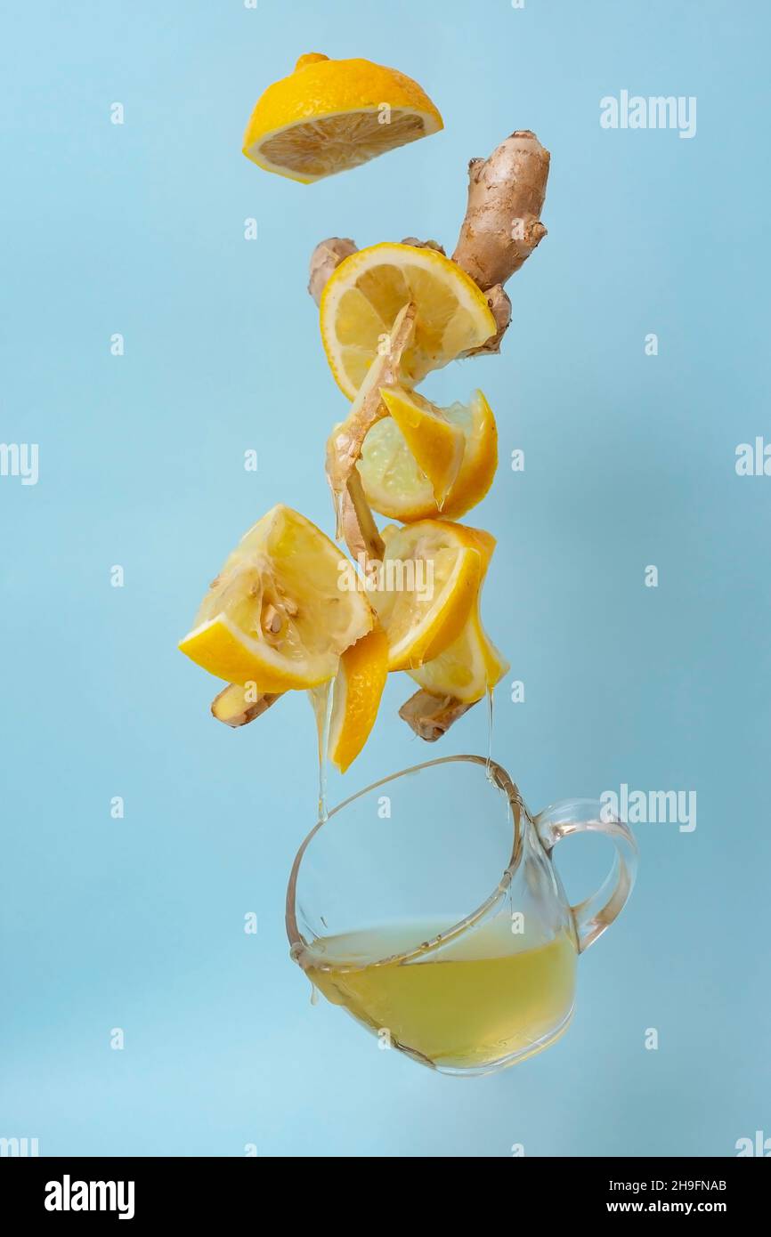 levitating honey lemon slices and ginger over a hot cup of tea, on blue ...