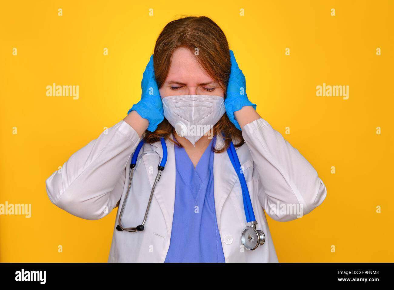 The doctor holds his hands over his head on a yellow background ...