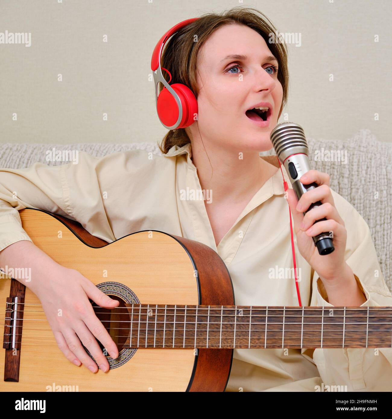 Happy woman musician with guitar in headphones sings song into ...