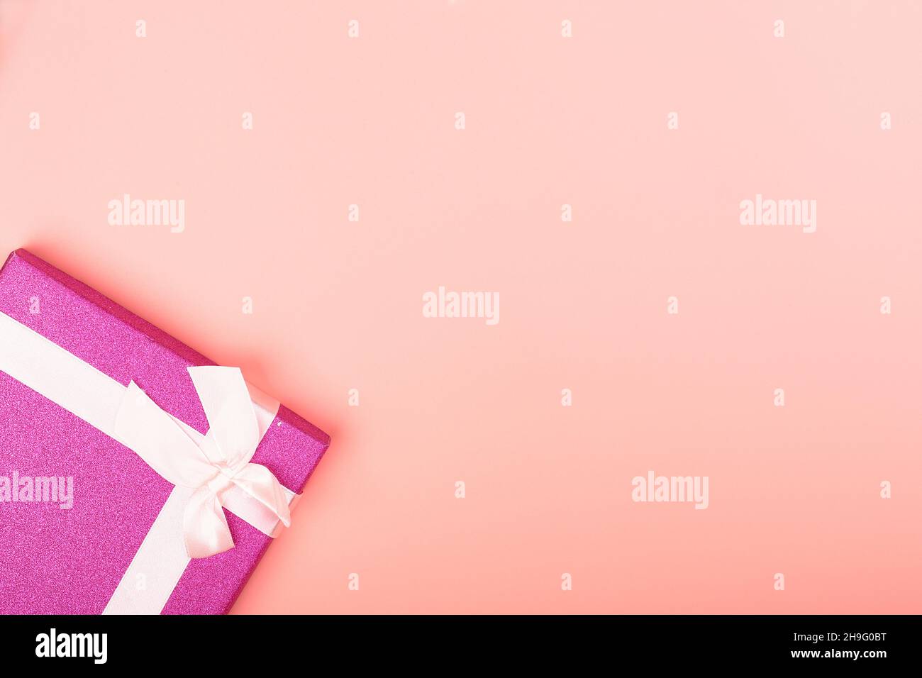 pink glitter gift box with ribbon on a pink background. minimalistic ...