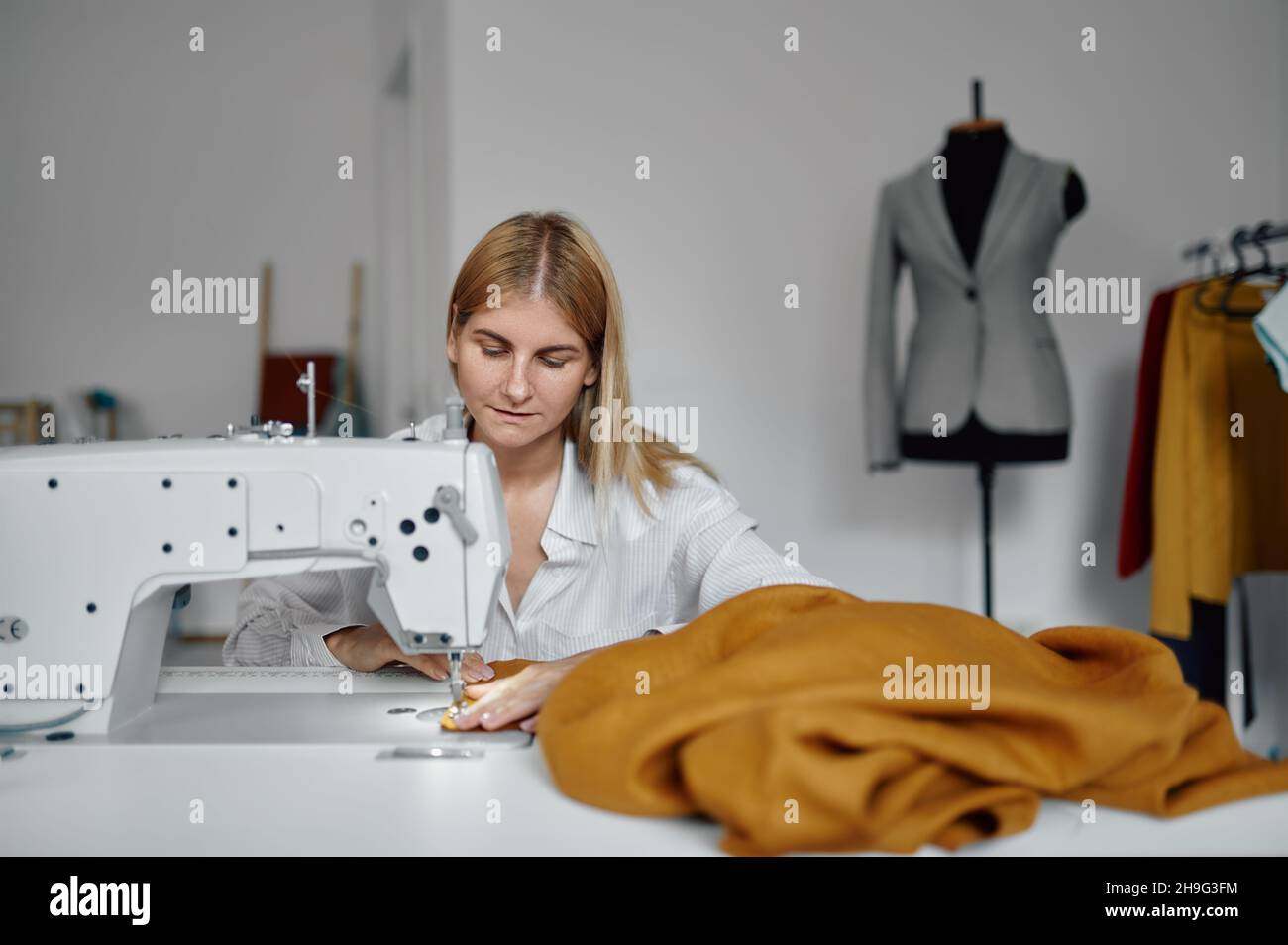 Dressmaker sews cloth on sewing machine, workshop Stock Photo - Alamy