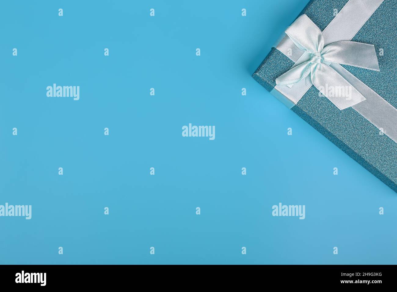 Christmas background. Blue glitter gift box with bow on a blue ...