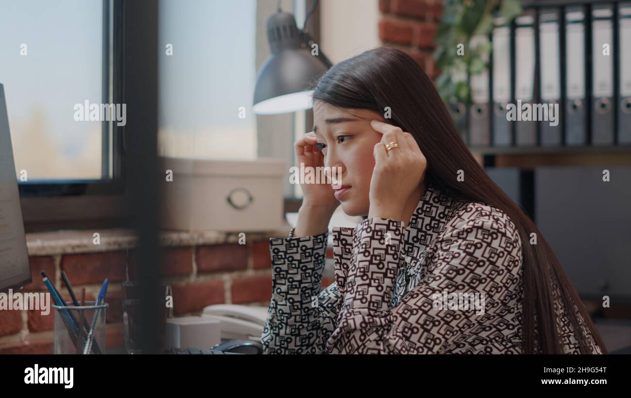 Close up of employee with headache rubbing temples to work on business ...