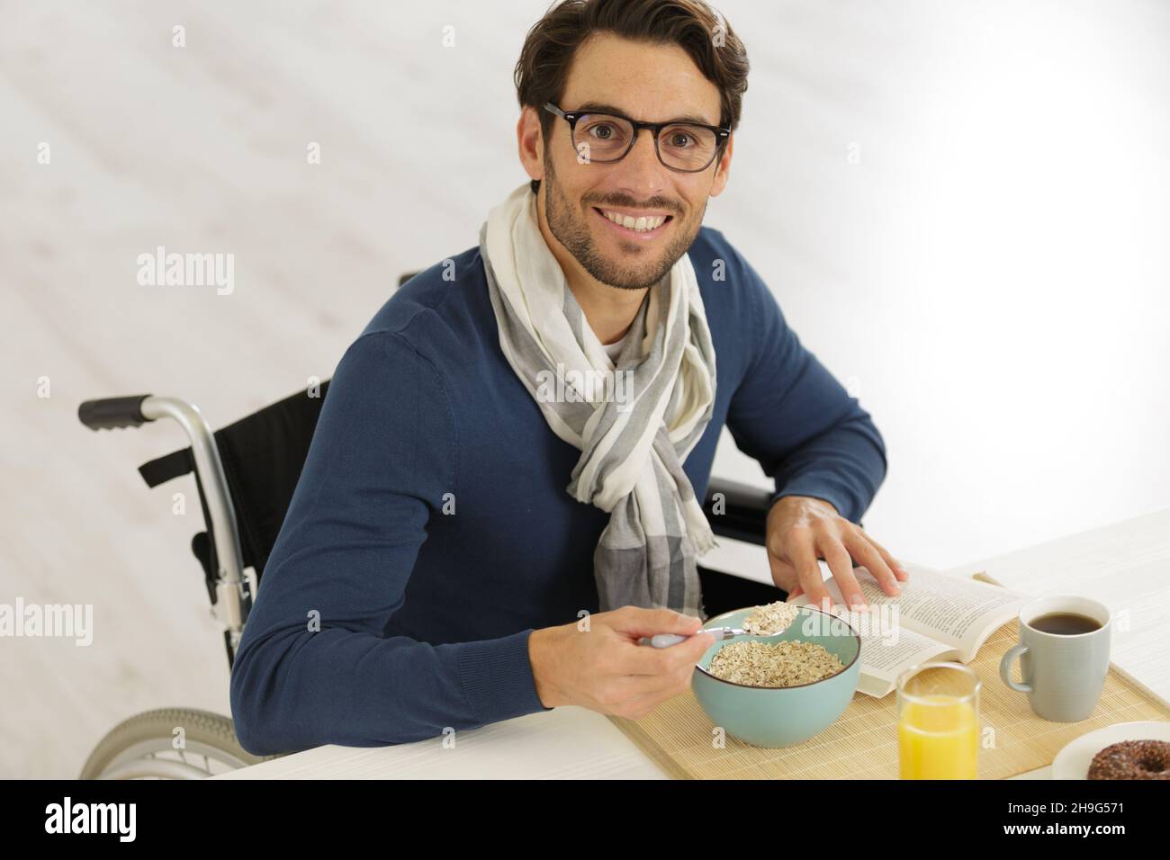positive disabled man having cereal in the living room Stock Photo - Alamy