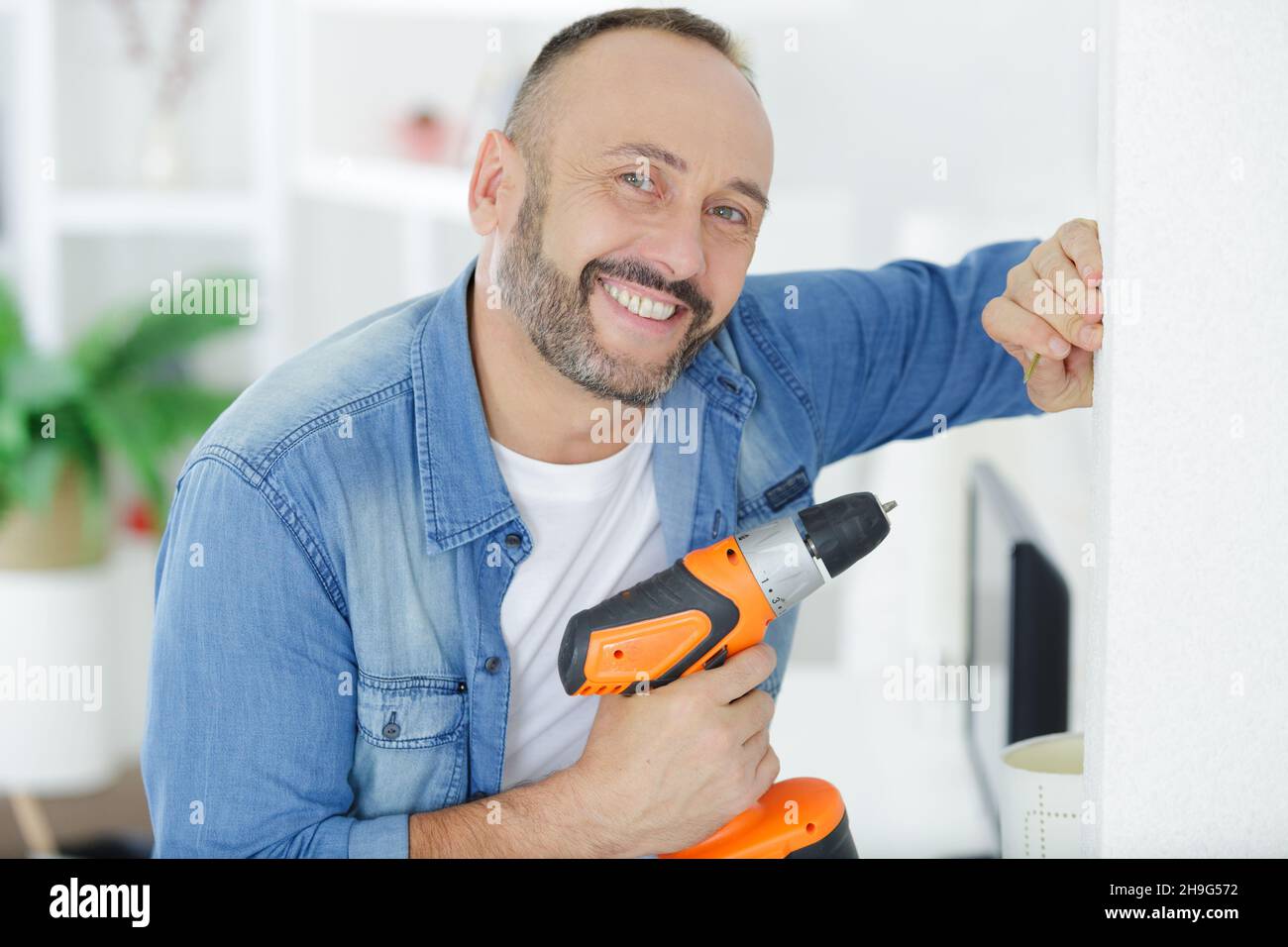 man drilling the wall with drill perforator Stock Photo - Alamy