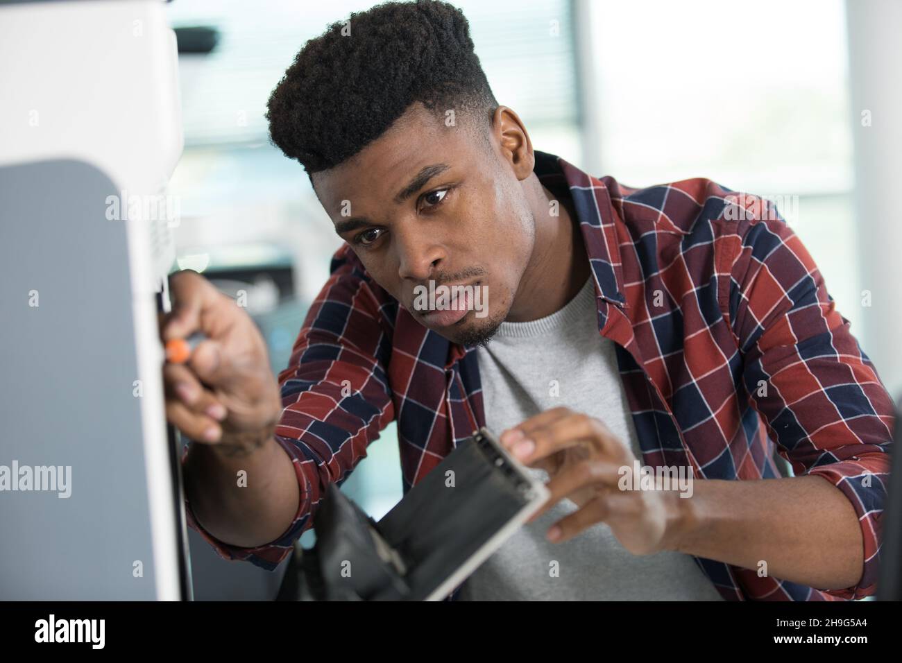 young worker holding a screwdriver in front of printer Stock Photo - Alamy