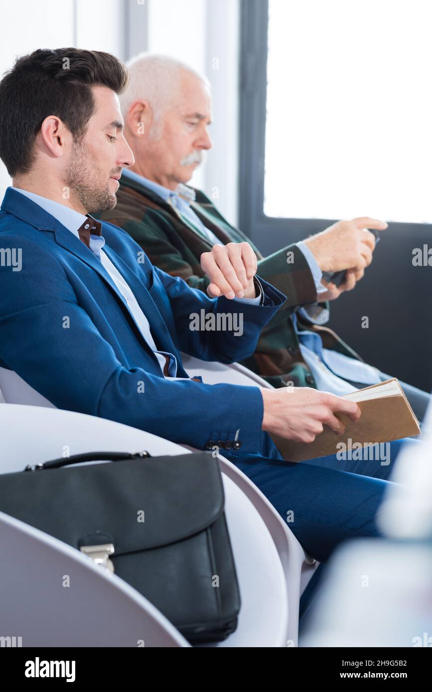 man in waiting room looking at watch another using smartphone Stock ...