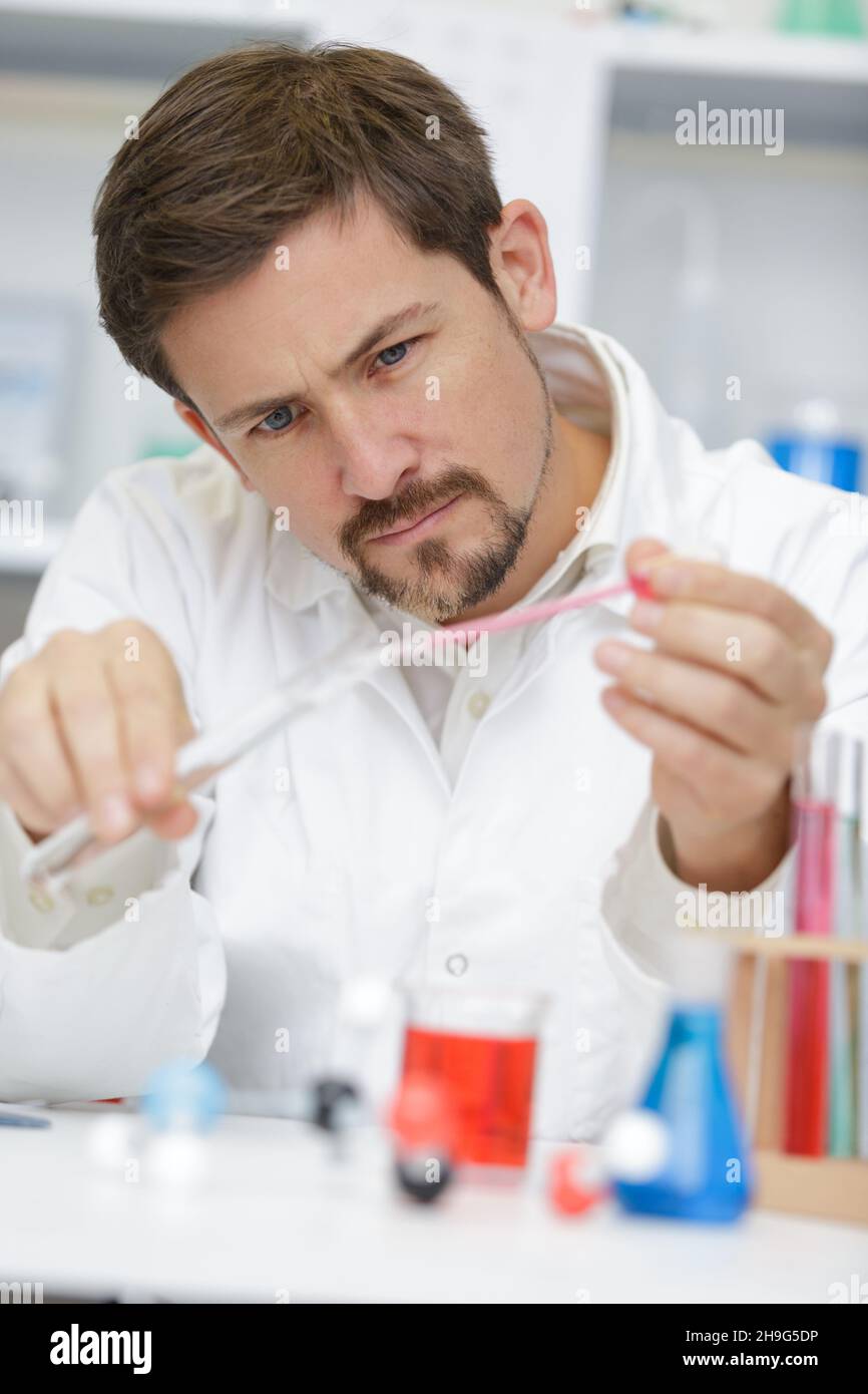 young man scientist using auto-pipette with flasks Stock Photo - Alamy
