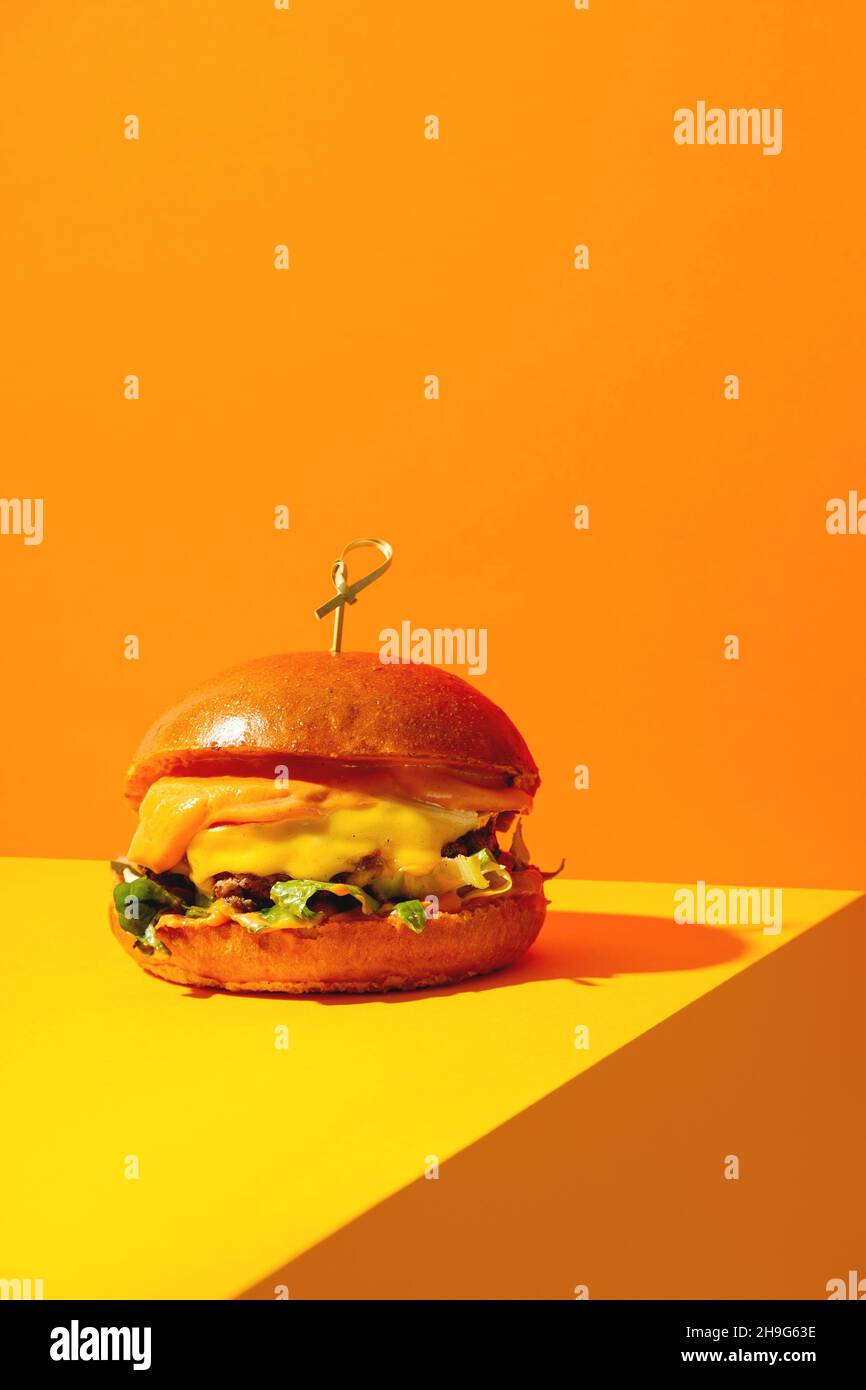 Big burger with cheese on bright orange and yellow background. American ...