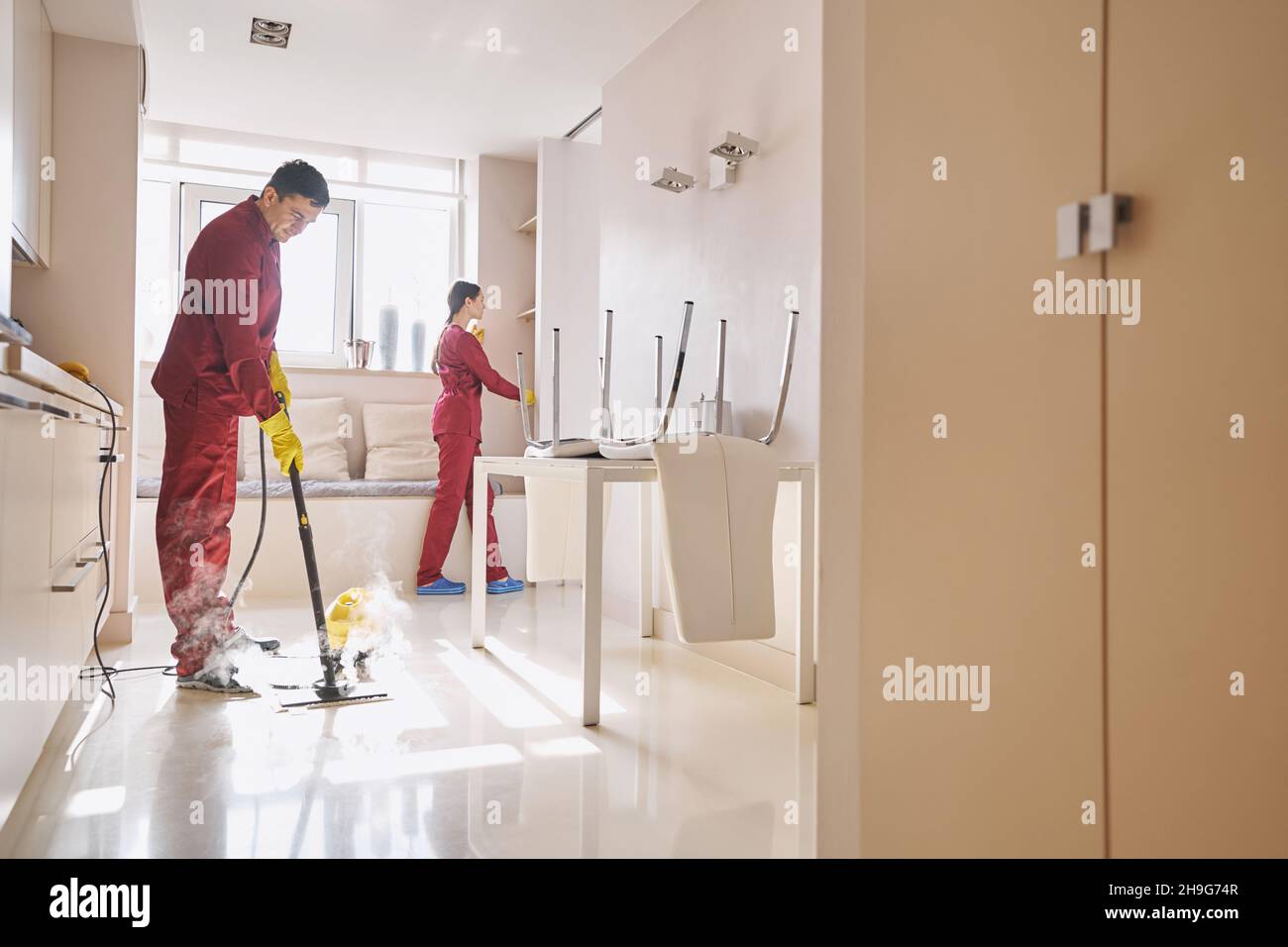 Two professional janitors in uniforms cleaning kitchen Stock Photo - Alamy