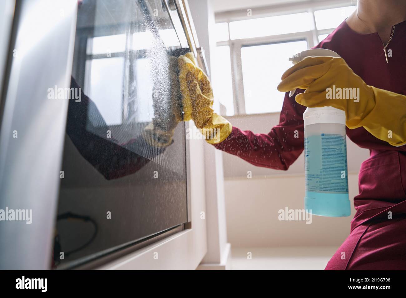 Janitor in rubber gloves cleaning part of electric stove Stock Photo ...