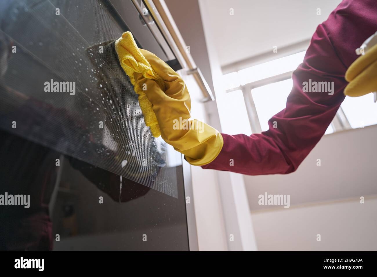 Professional janitor cleaning part of electric range Stock Photo - Alamy
