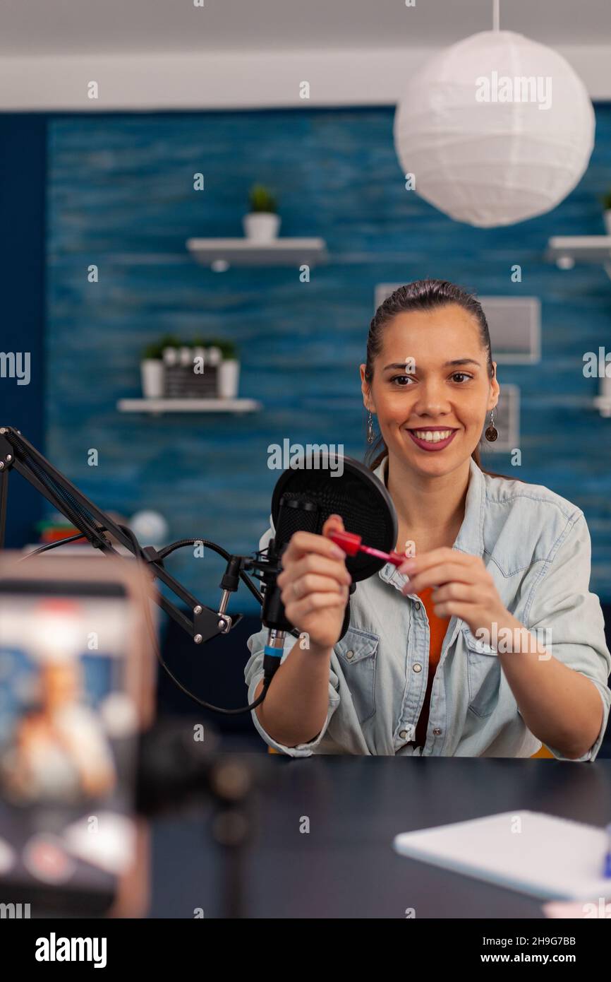 Smiling influencer filming lipstick review with mobile phone. Woman ...