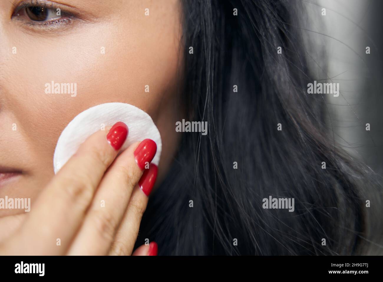 Woman with cotton pad in hand cleaning her face Stock Photo - Alamy
