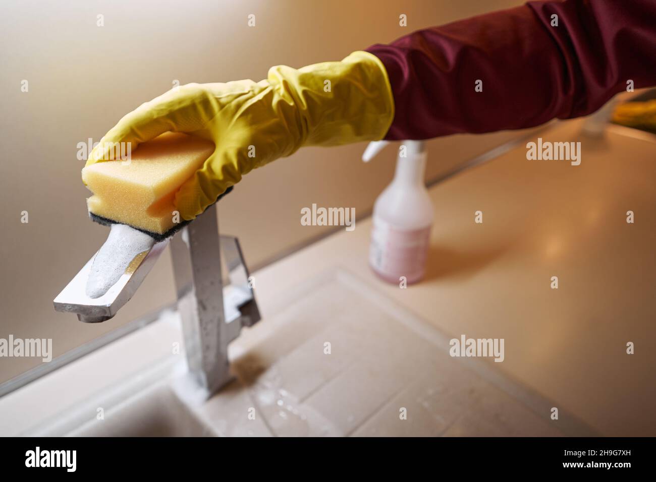 Gloved hand of cleaner washing kitchen chrome faucet Stock Photo - Alamy