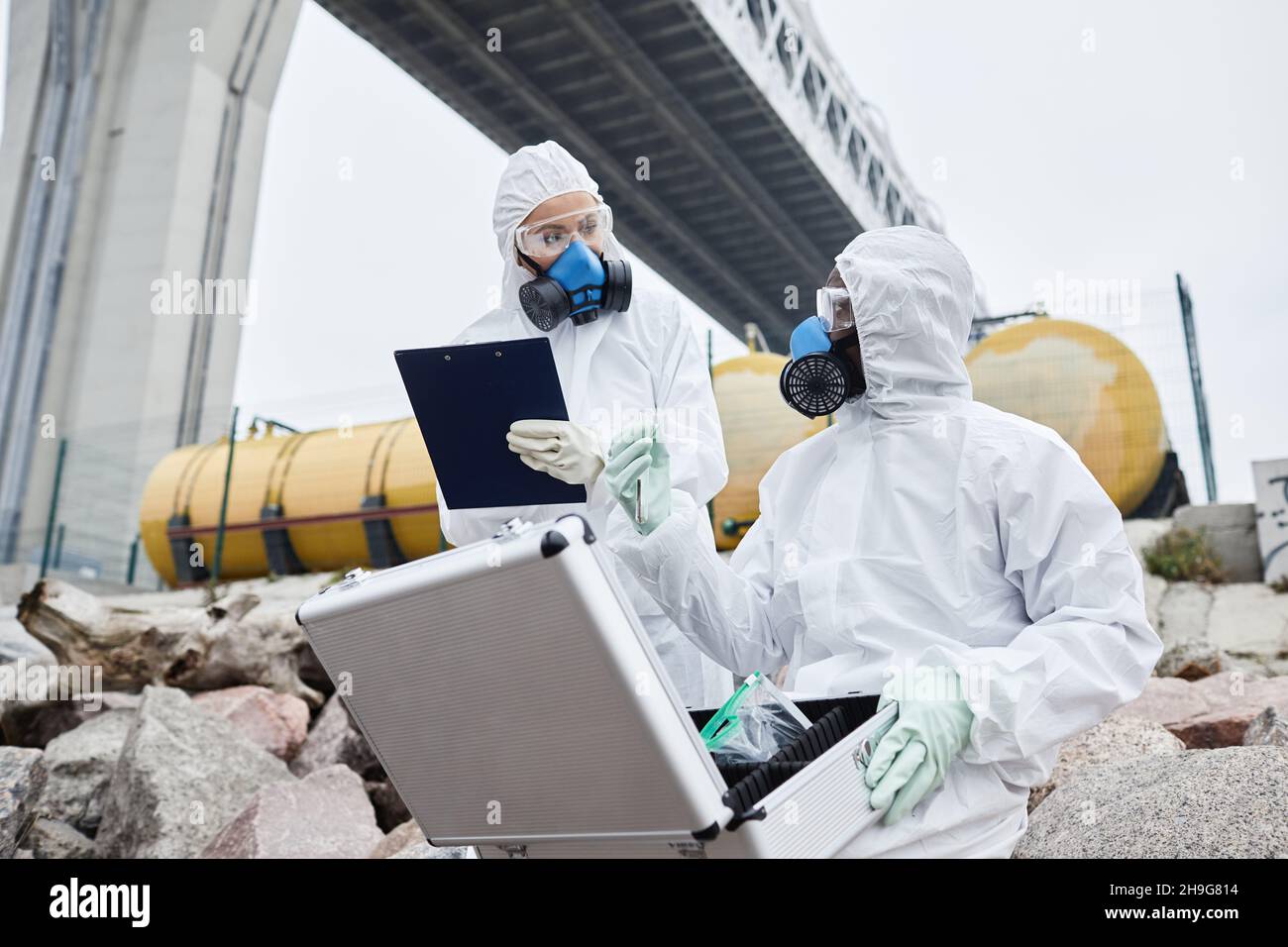 Portrait of two scientists wearing hazmat suits collecting samples ...