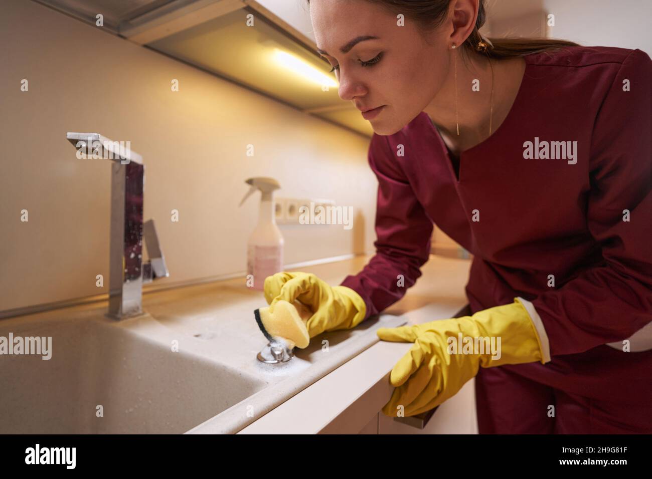 Concentrated serious professional janitor cleaning kitchen counter ...