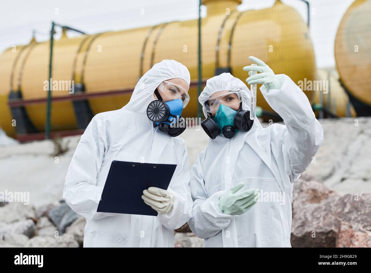 Waist up portrait of two female scientists wearing hazmat suits ...