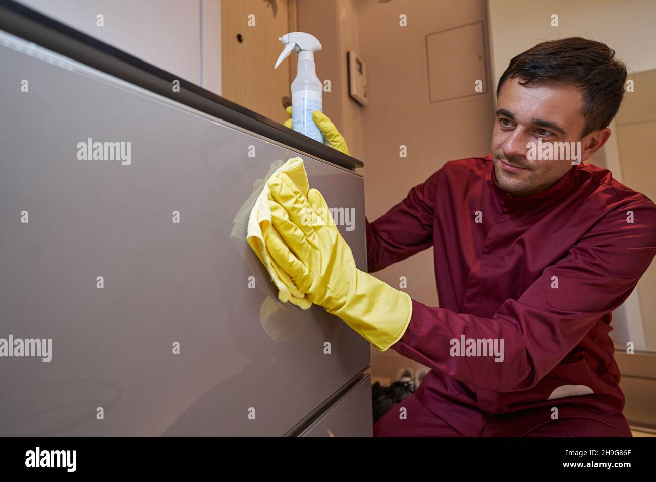 Professional cleaner in rubber gloves dusting shoe rack cabinet Stock ...
