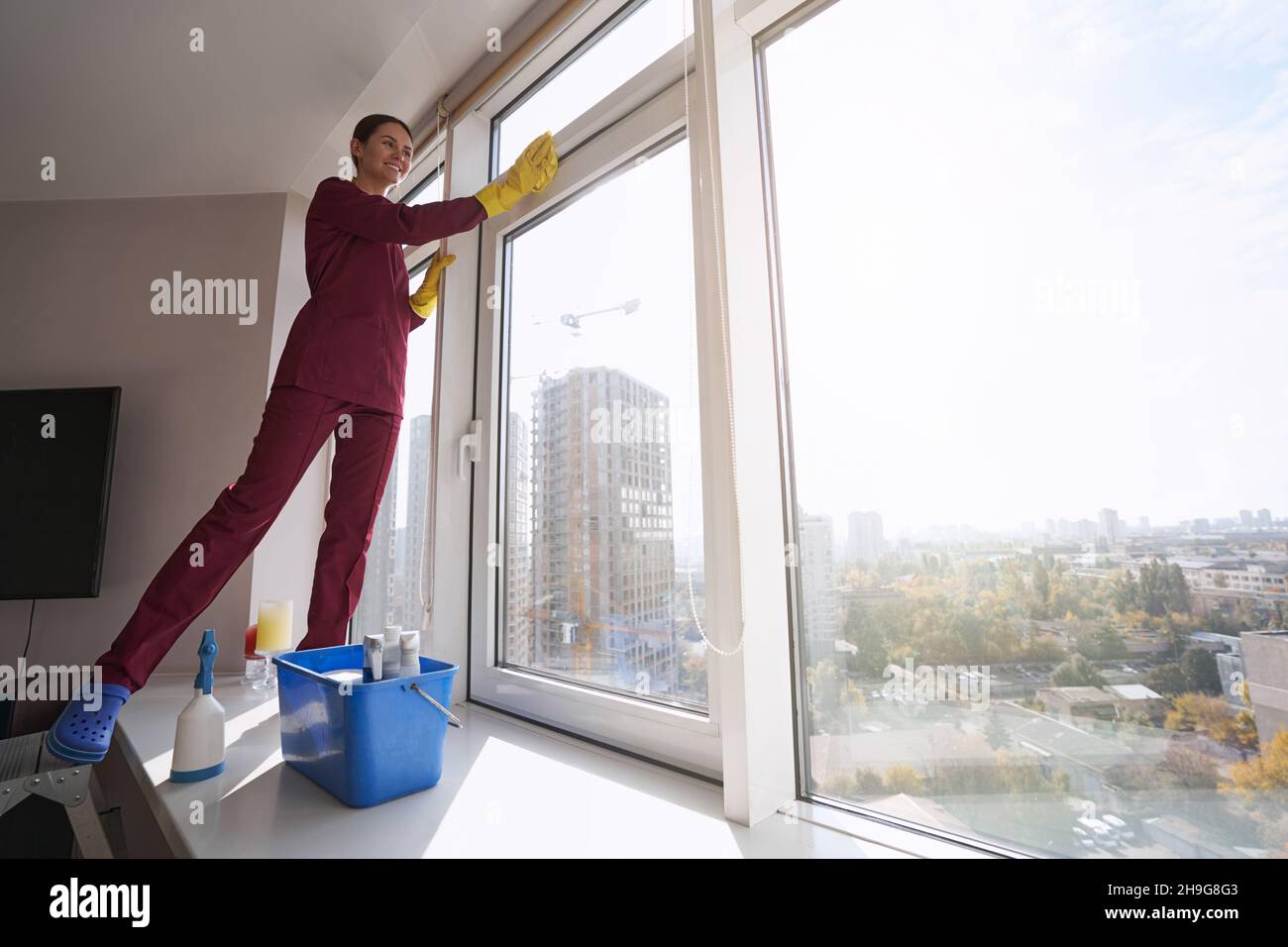 Joyous woman standing on windowsill and cleaning window Stock Photo - Alamy