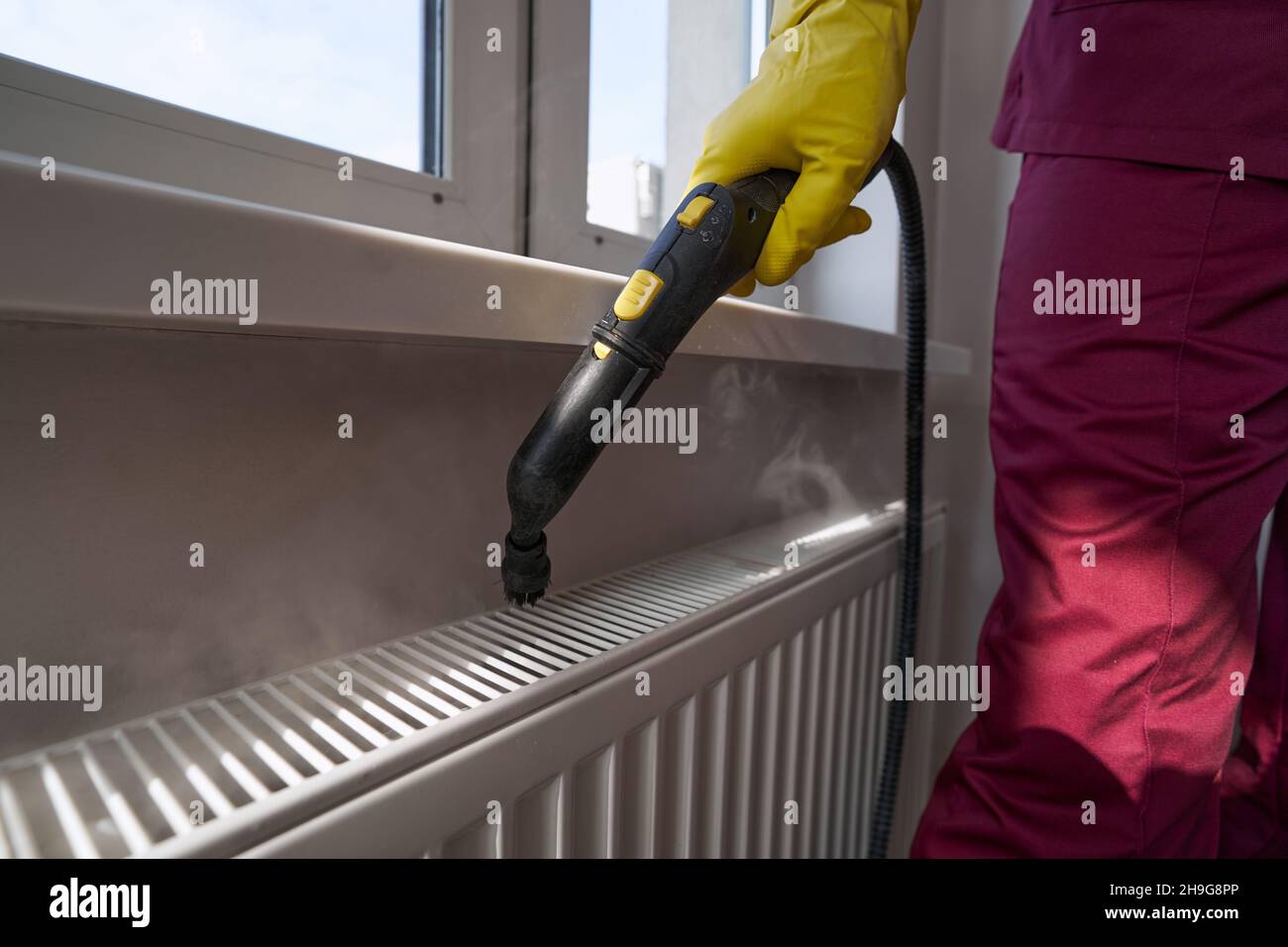 Experienced janitor in uniform steam-cleaning domestic radiator Stock ...